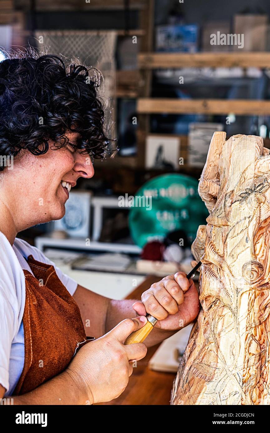 Sculptress carving wooden figure. First plane Stock Photo - Alamy