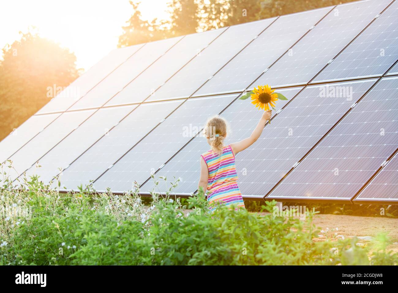 Young 6 year old blonde girl child standing in front of small solar ...