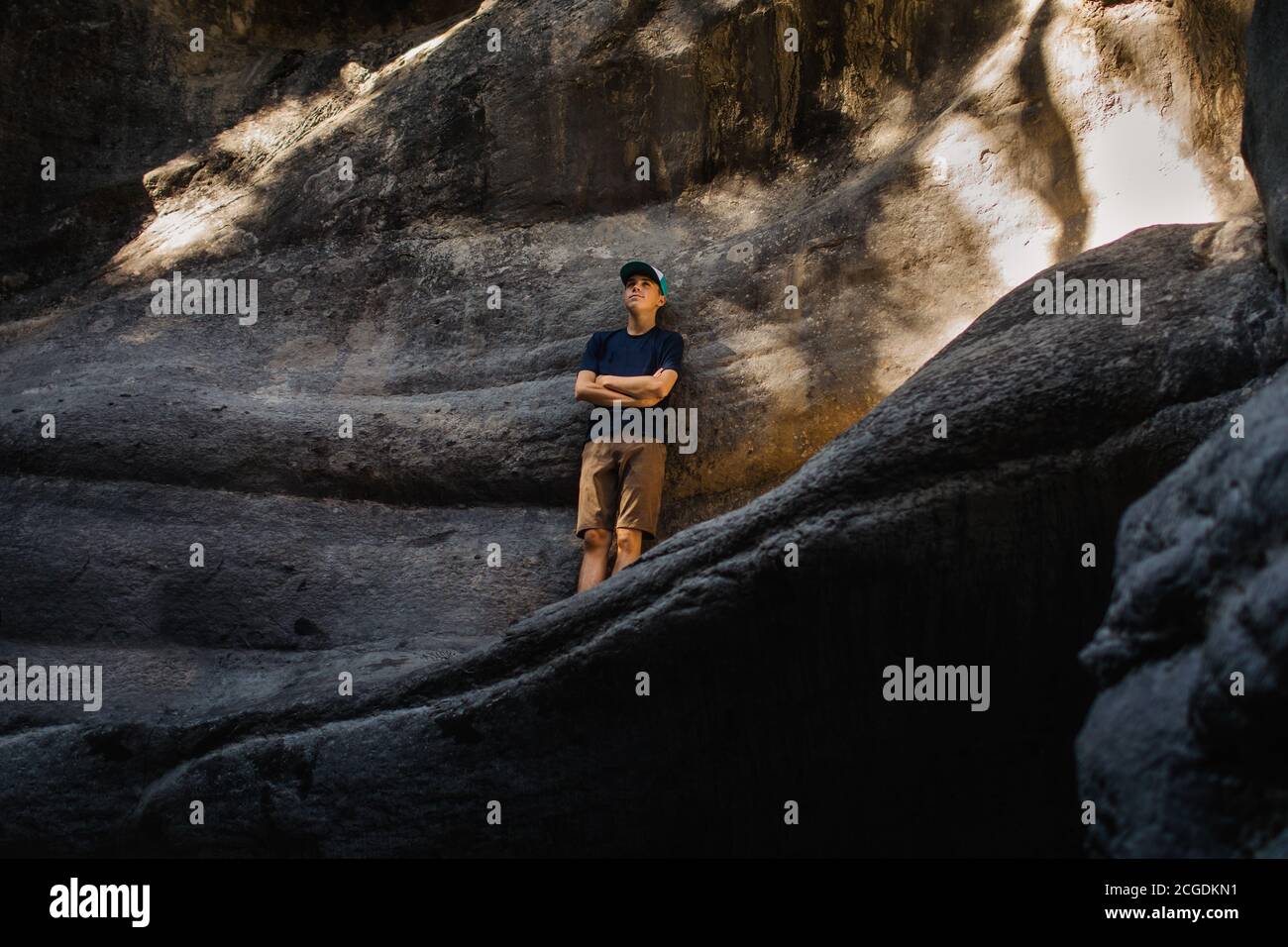 Tens boy leaning up against rock Stock Photo - Alamy