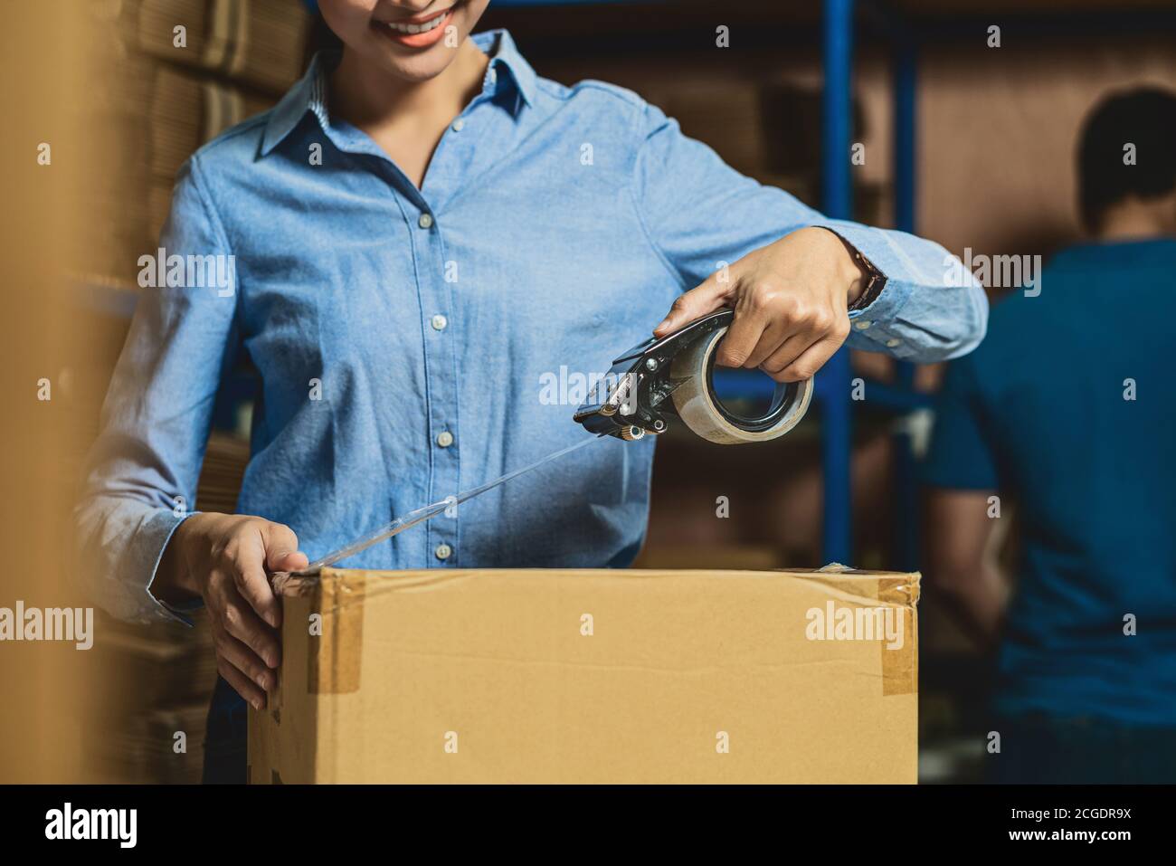 Closeup of Warehouse worker woman packing cardboard box with sticky ...