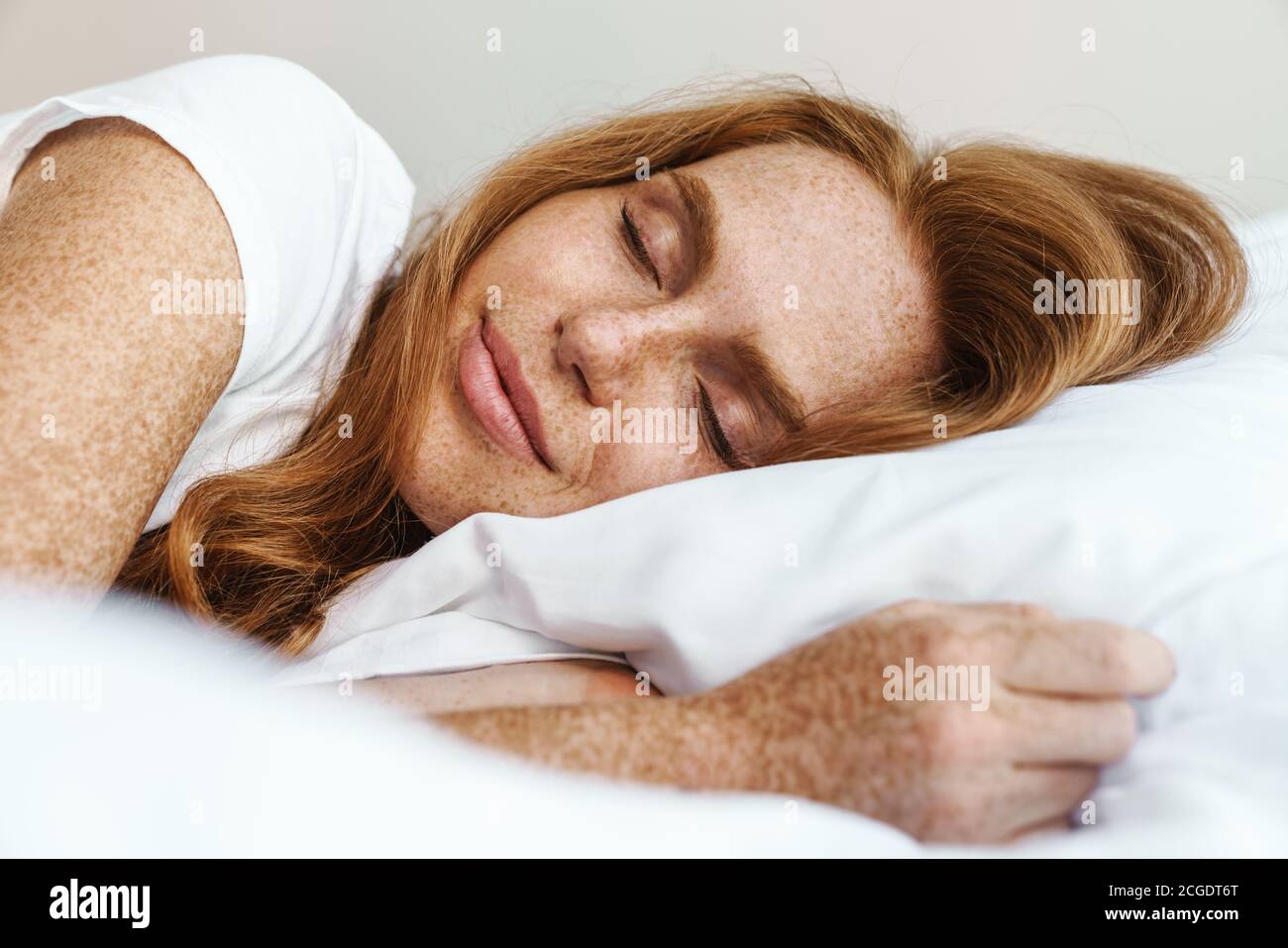 Image of ginger happy woman with freckles sleeping while lying in bed ...