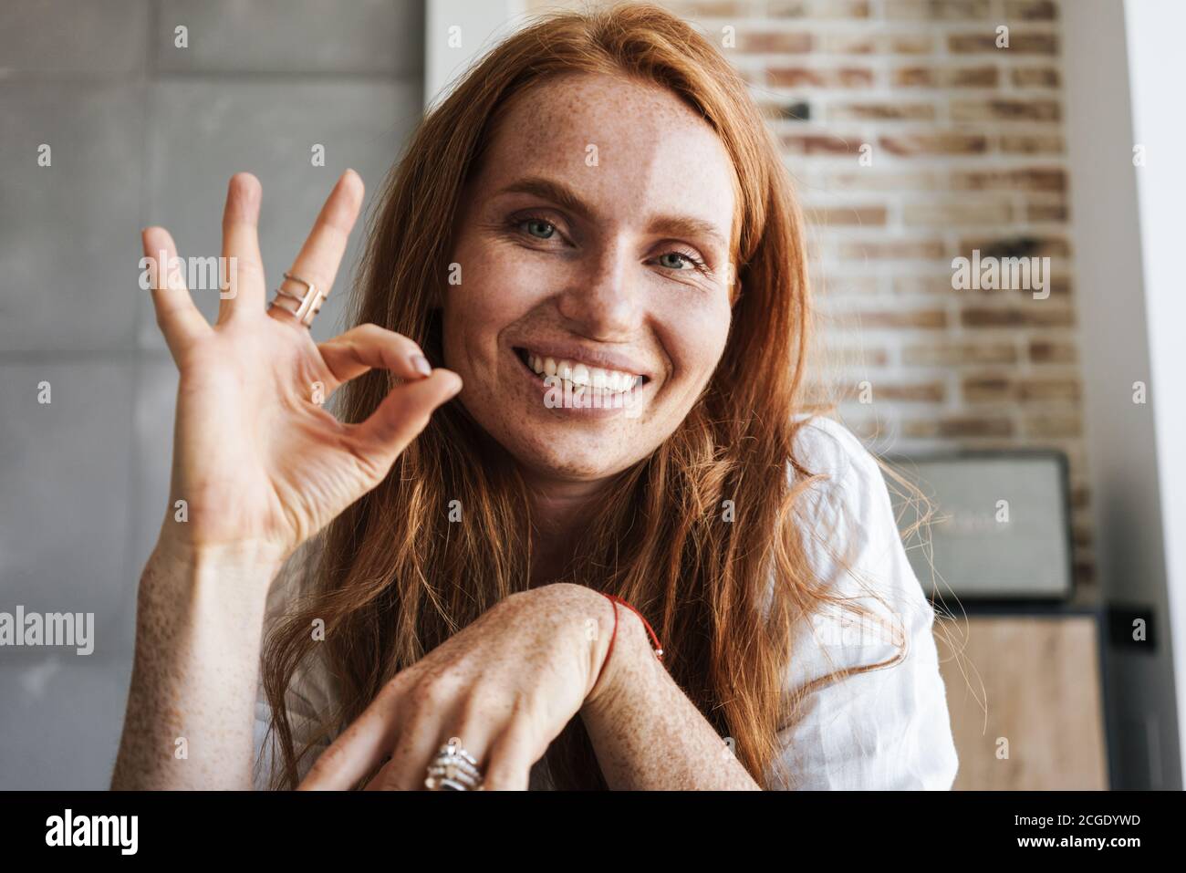 Image of happy ginger woman with freckles smiling and showing ok sign ...