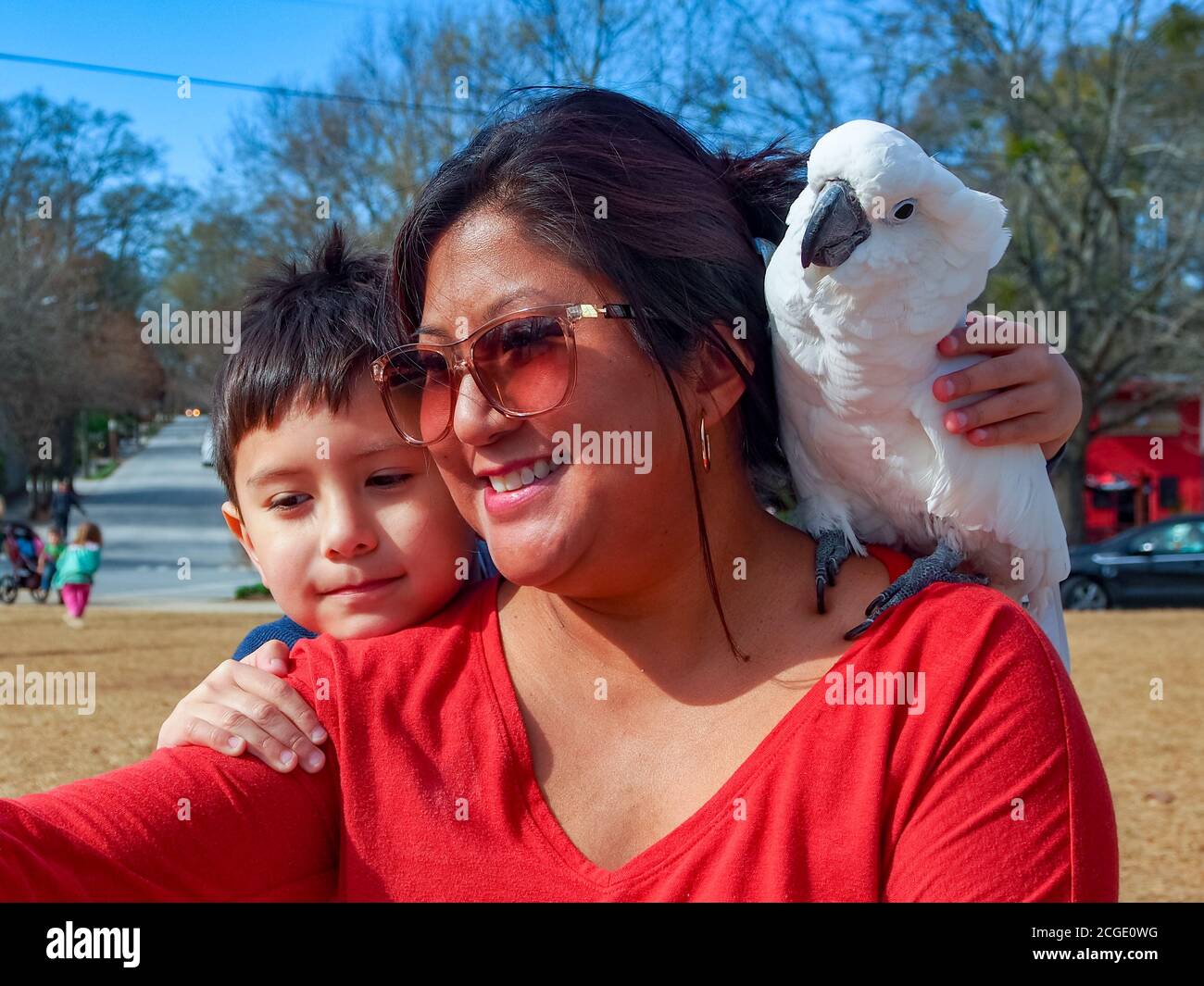 A woman and her young son taking a photo with a white cockatoo on her ...