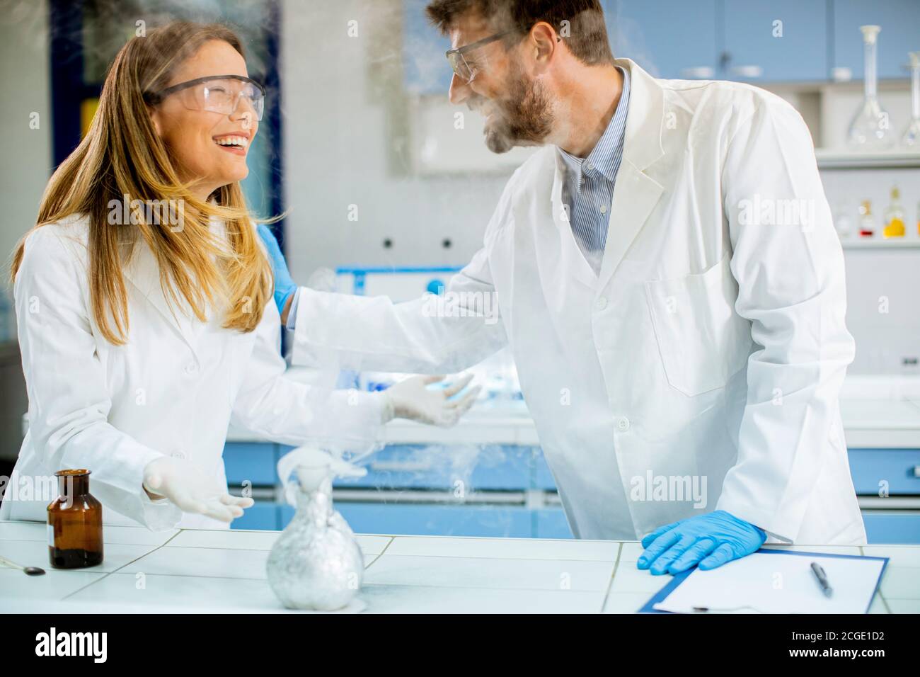 Young researchers doing experiment with smoke on a table of a chemical ...