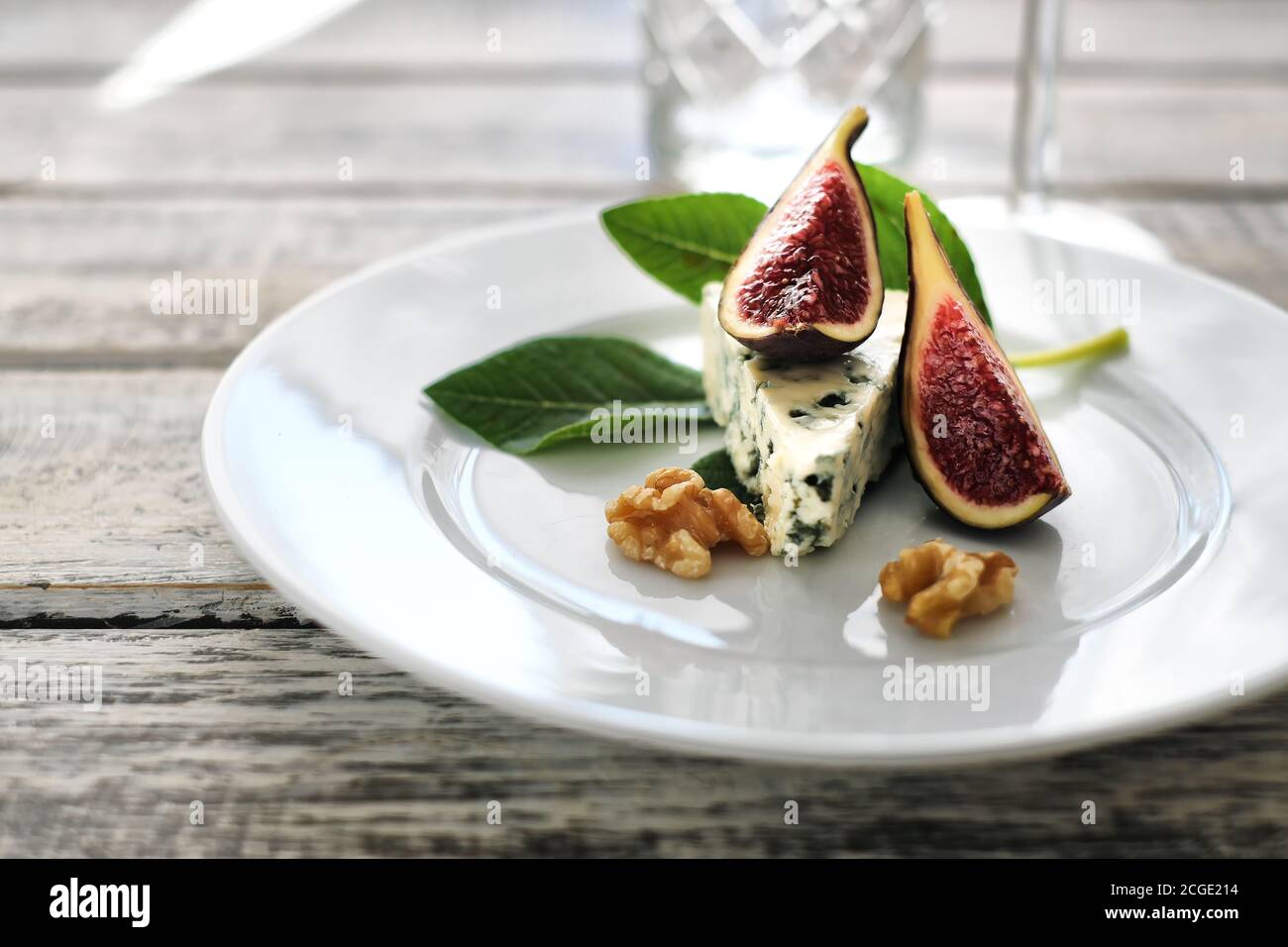 Figs nicely arranged on a white plate with blue cheese and a fig leaf ...