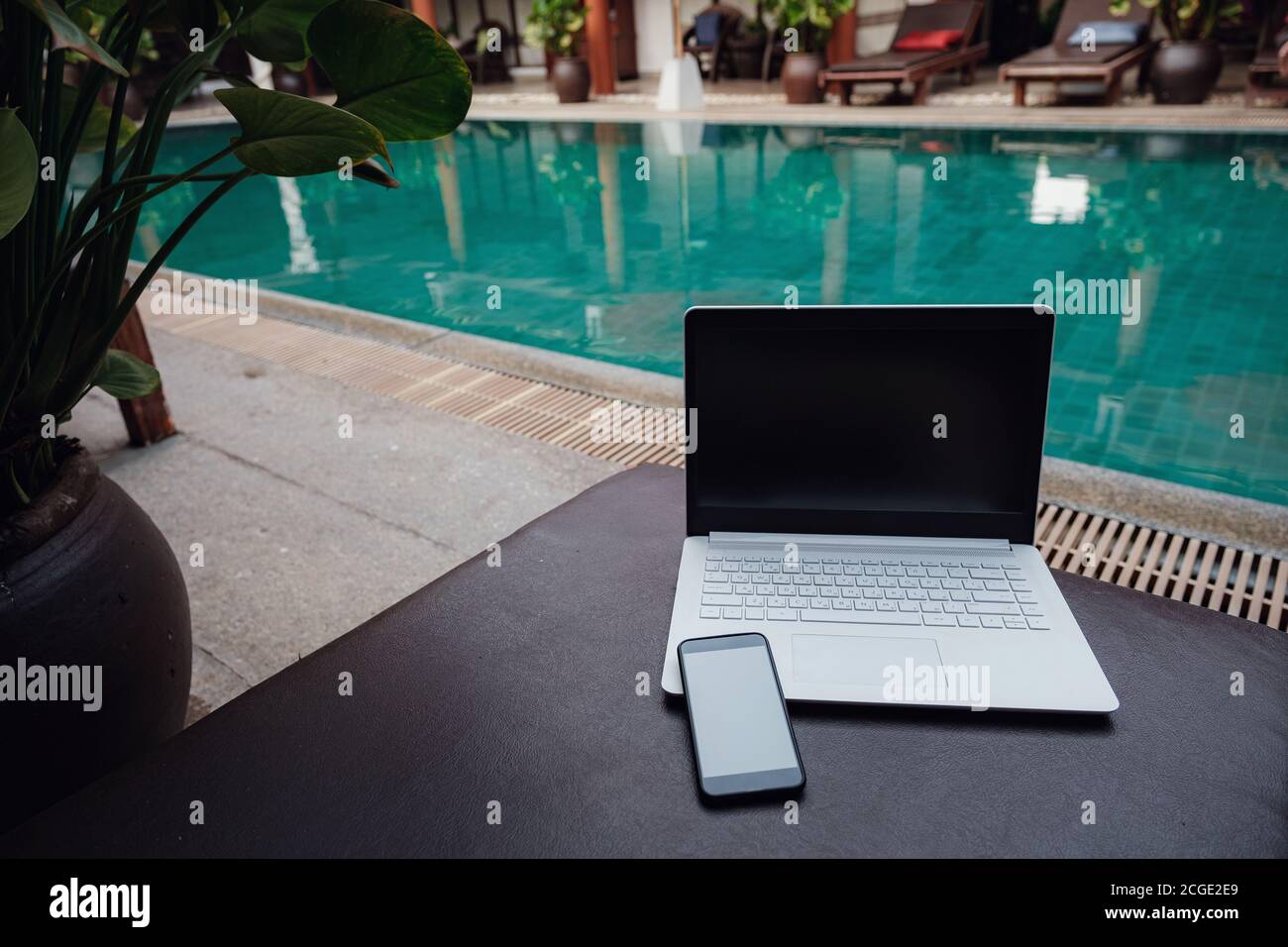 White Laptop at the swimming pool and smartphone, workspace at a ...