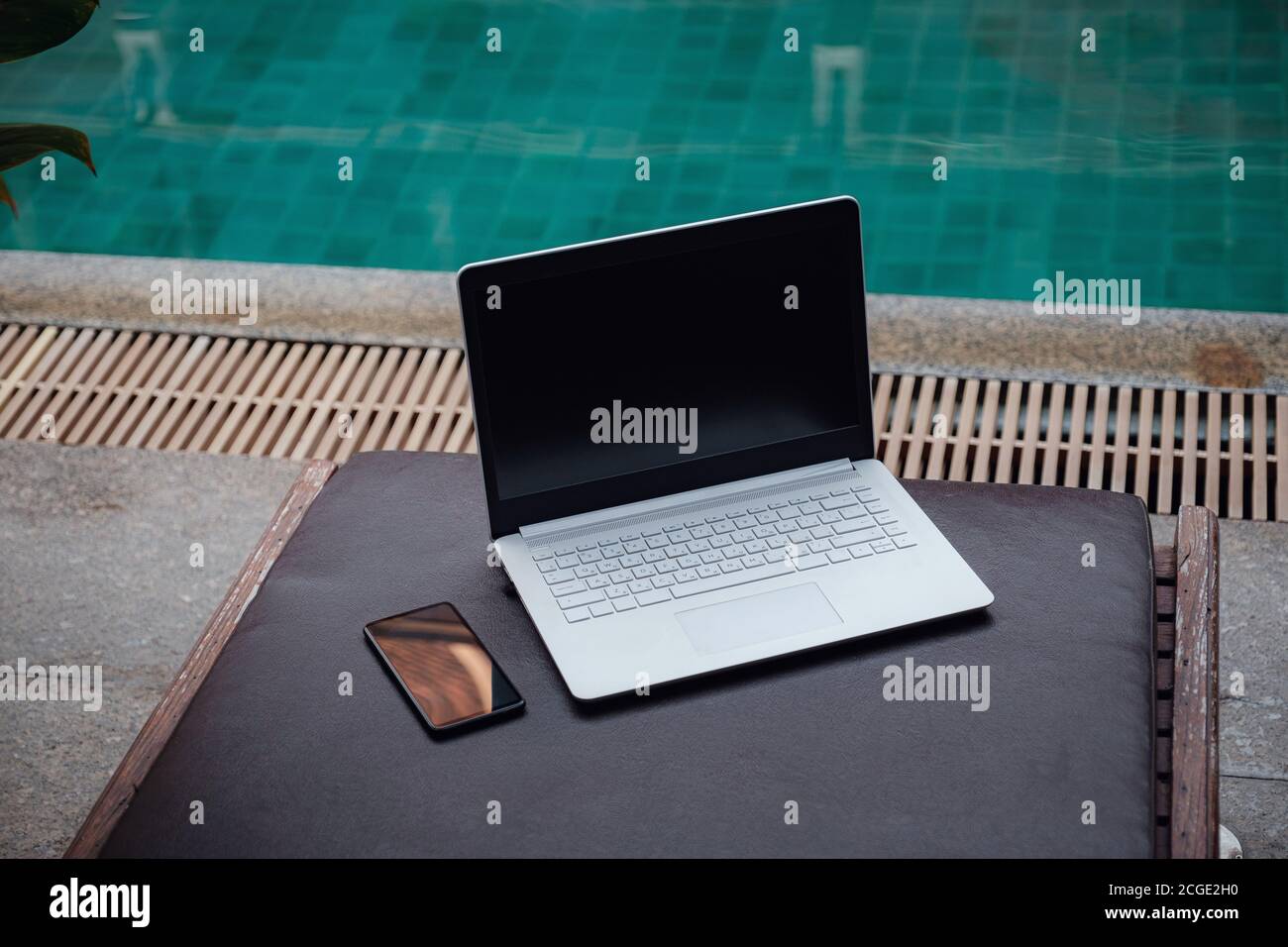 White Laptop at the swimming pool and smartphone, workspace at a ...