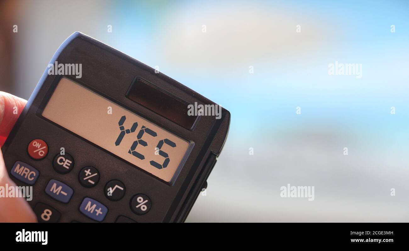 Calculator with YES on display on blue blured background. Positive ...