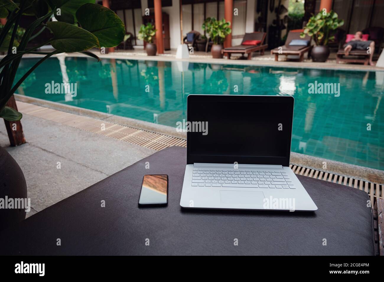 White Laptop at the swimming pool and smartphone, workspace at a ...