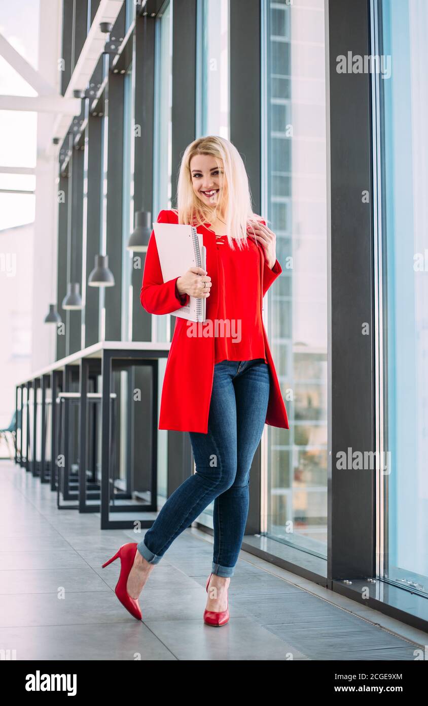 Attractive successful business lady in a red suit in a light office ...
