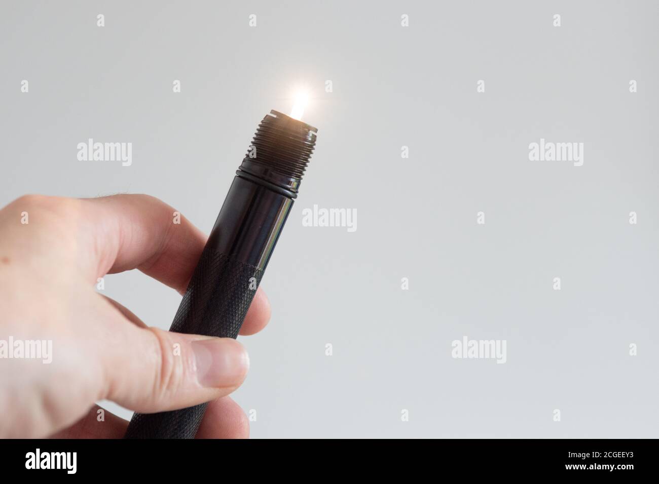 Human hand holding small torch or flashlight, maglite with head removed ...