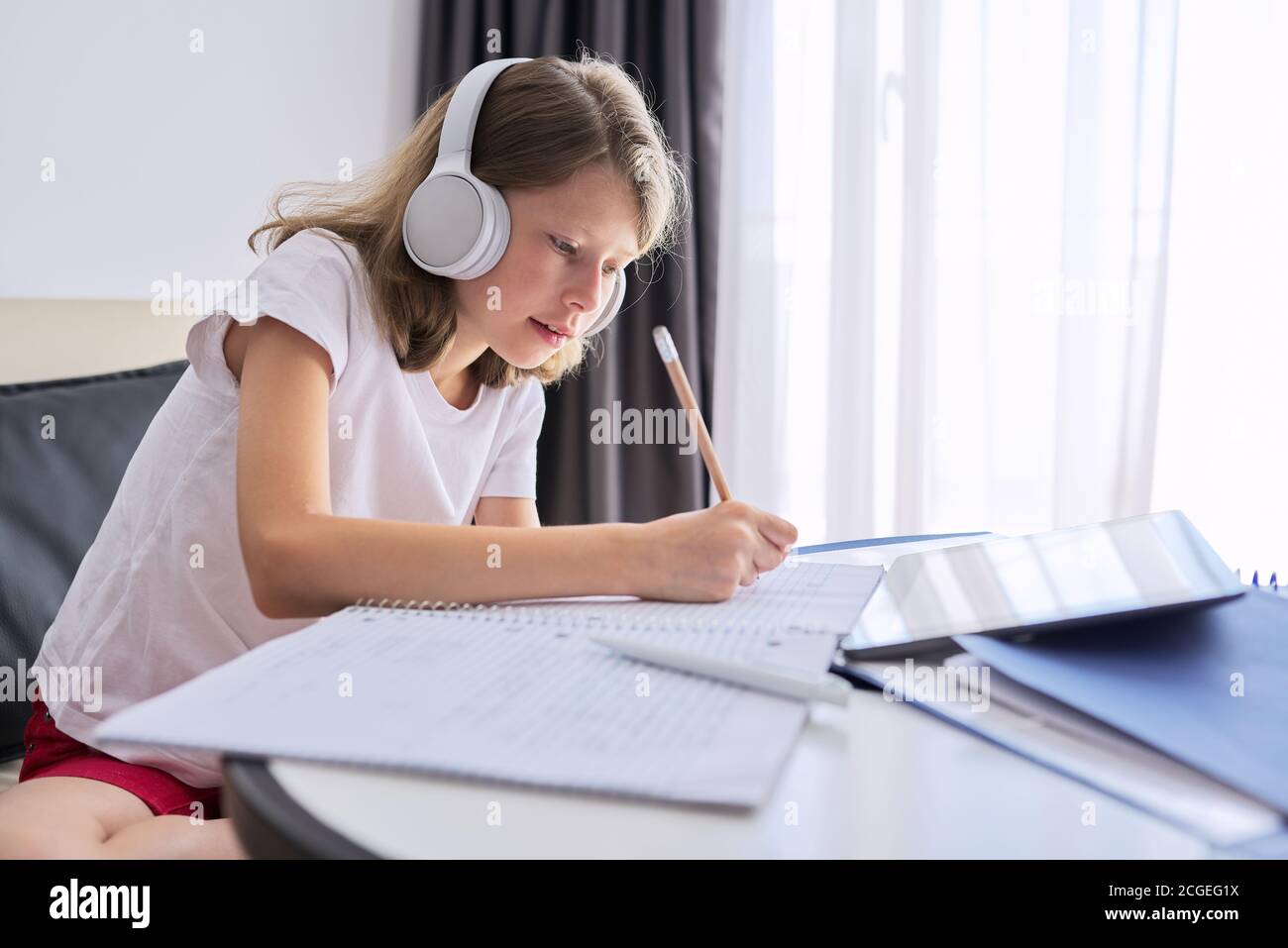 Child with digital tablet and headphones writing in notebook Stock ...