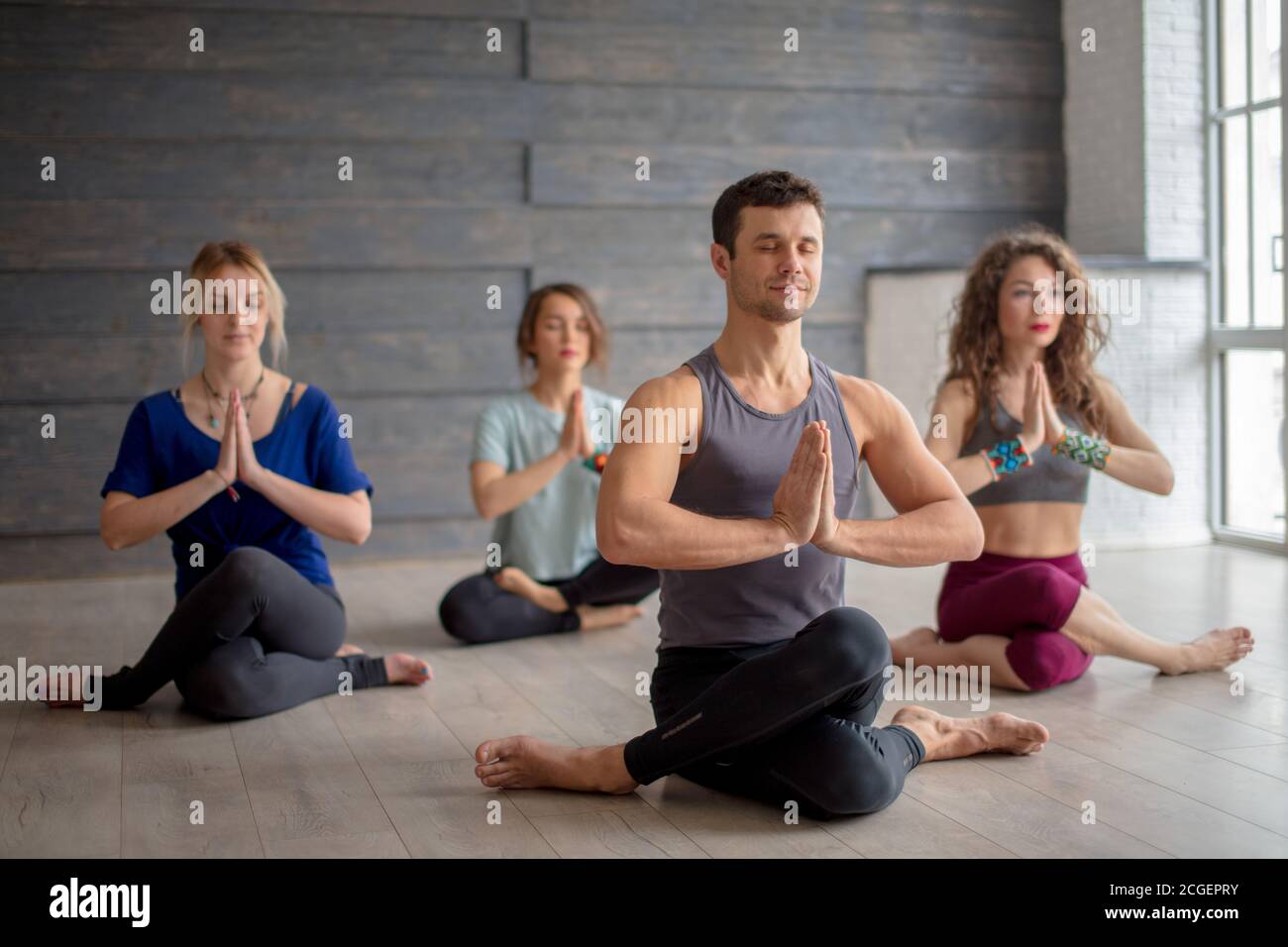 Handsome young muscular man, yogi teacher conducting yoga to caucasian ...
