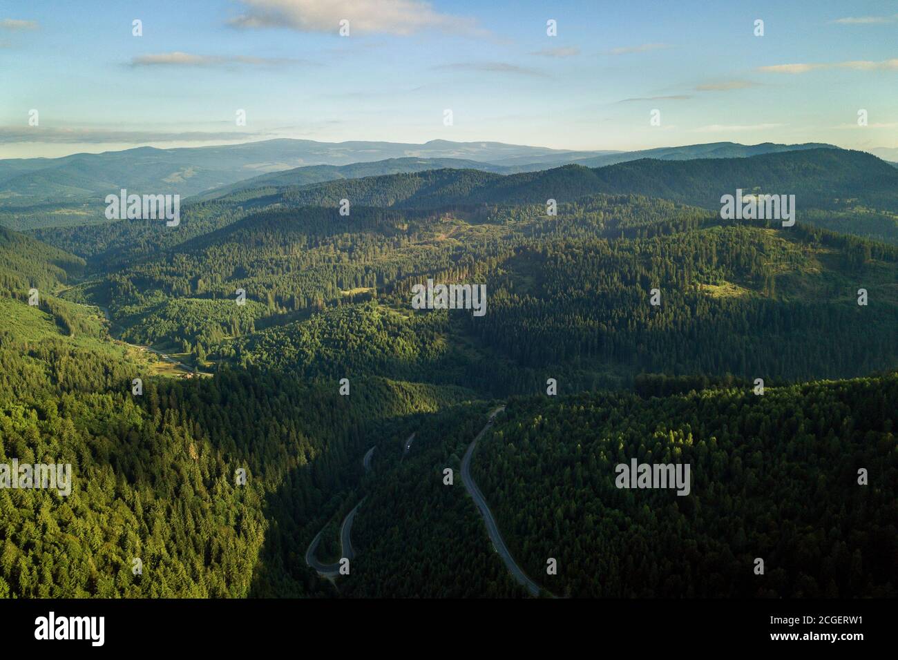 Aerial view of winding road in high mountain pass trough dense green ...