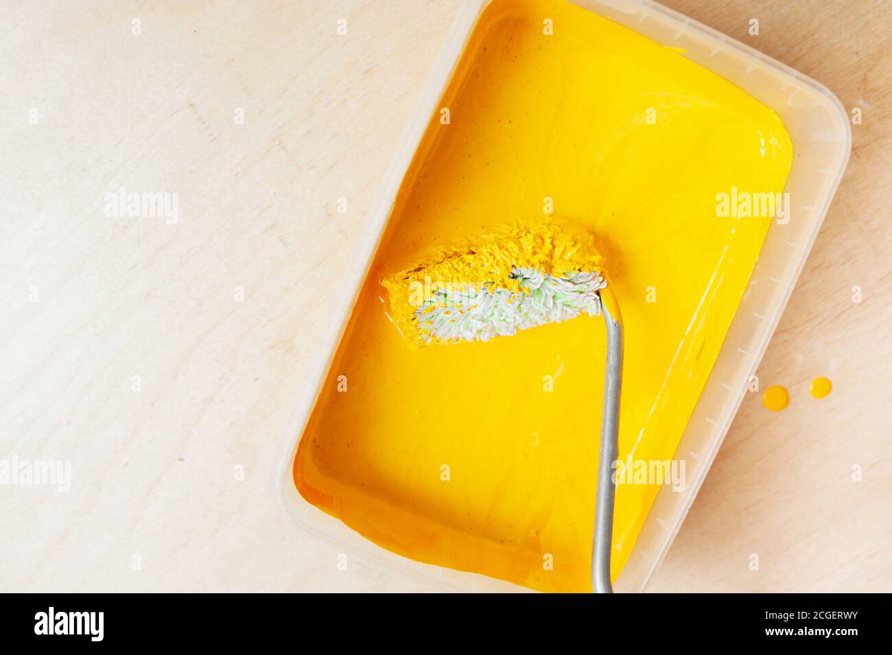 roller collects a bright yellow paint before painting from a ...