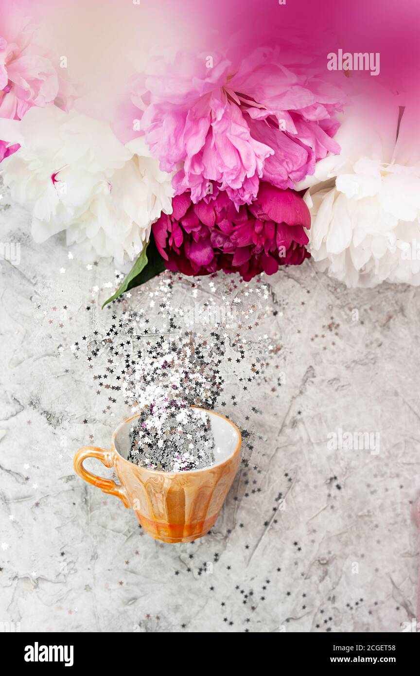 small gold cup filled with silver spangles stars and saucer on a light ...