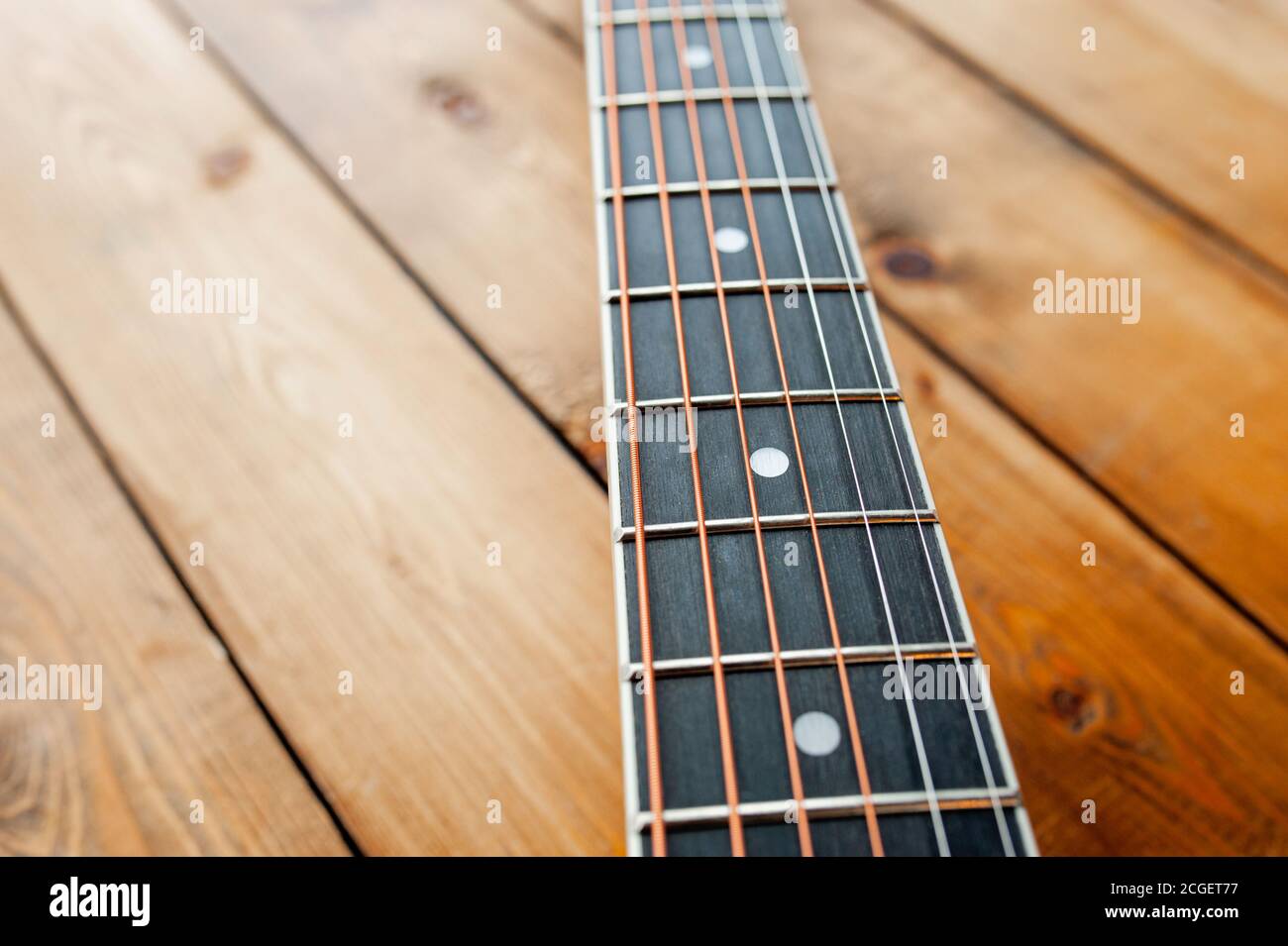 metal strings on the neck of an acoustic guitar on wooden boards, close ...