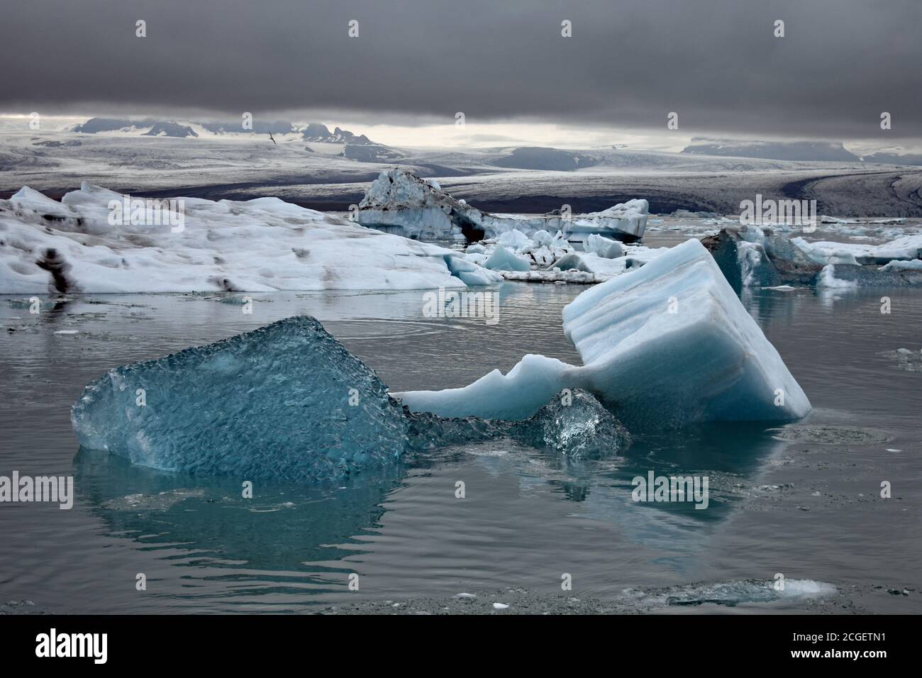 A overturned iceberg glows a bright blue colour in Jökulsárlón Glacier ...