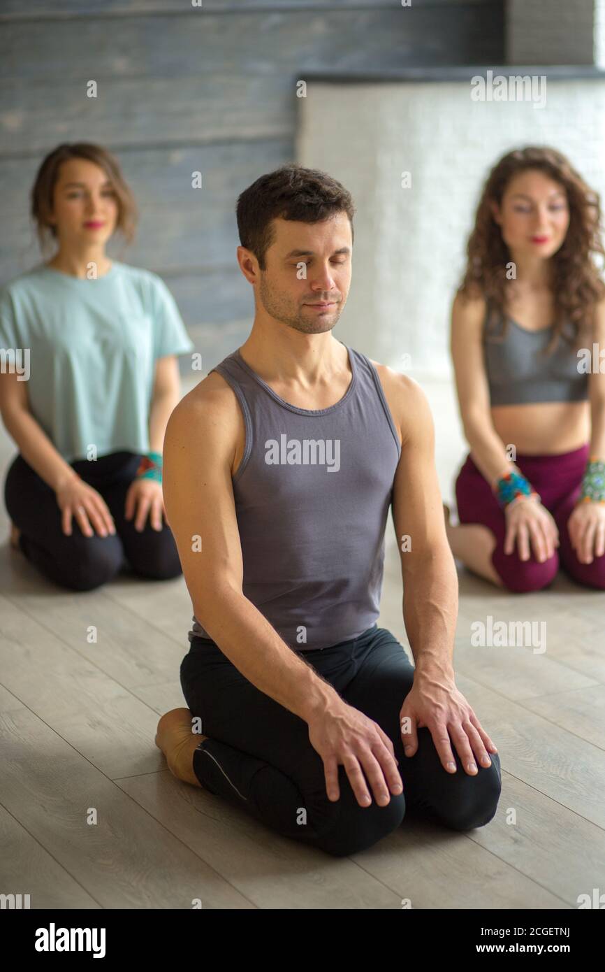 Handsome young muscular man, yogi teacher conducting yoga to caucasian ...