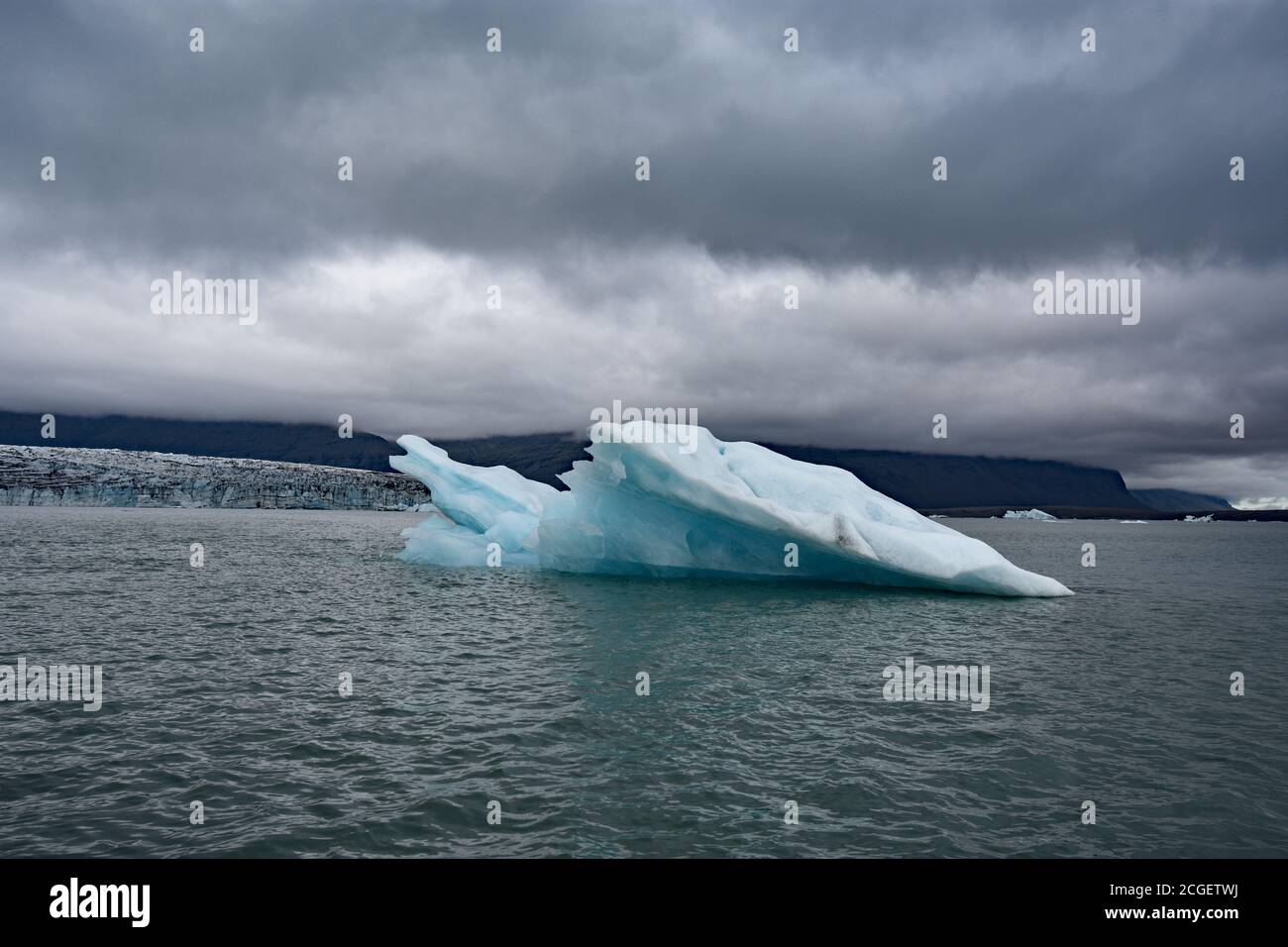 A large blue coloured iceberg floats on its own in front of ...