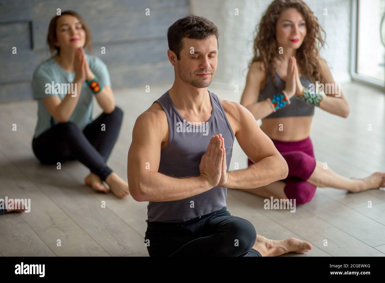 Handsome young muscular man, yogi teacher conducting yoga to caucasian ...