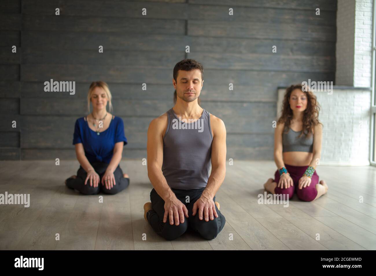 Handsome young muscular man, yogi teacher conducting yoga to caucasian ...