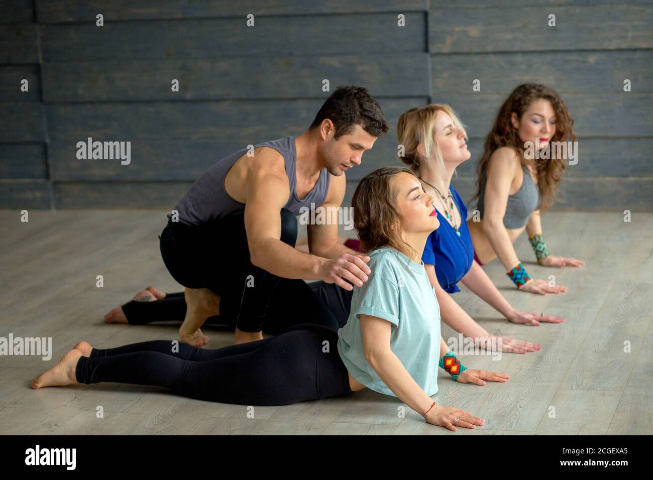 Athletic Man Yoga instructor teaching yoga to three young women in ...