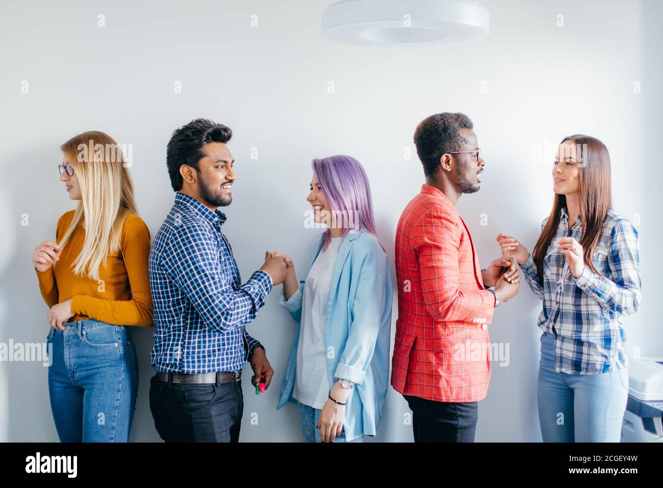 Diverse people holding hands and looking at each other over . Standing ...
