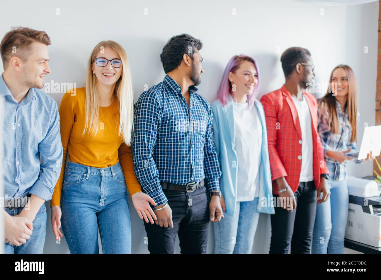 Group of happy diverse people standing in row against grey wall ...