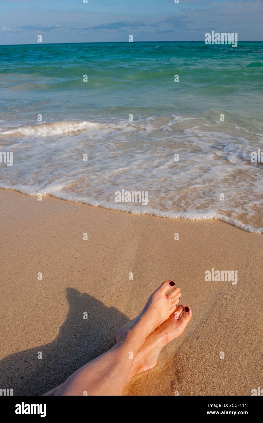 Feet on the white sand beach in Playa del Carmen on the east coast of ...
