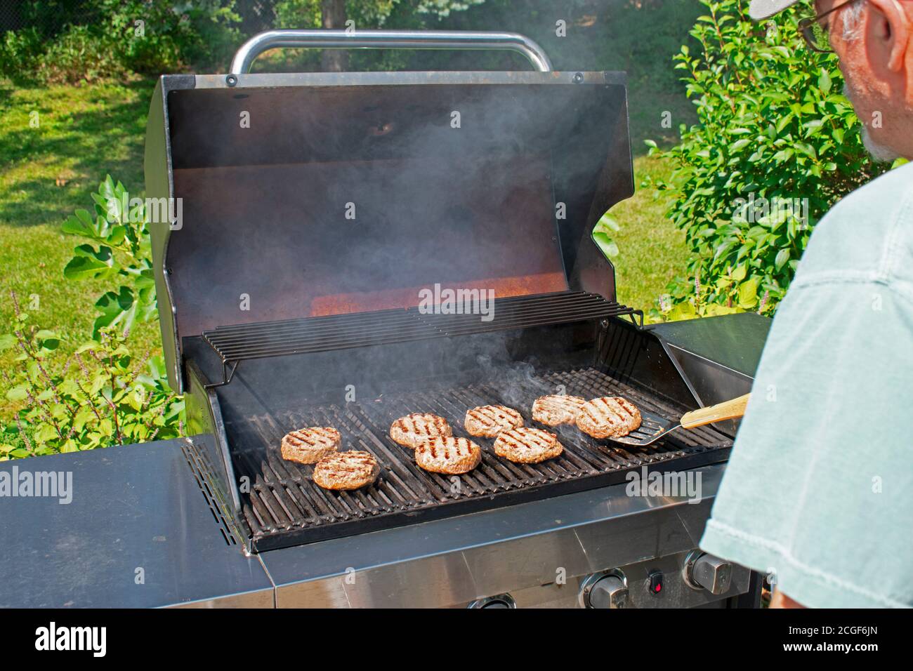 Person grilling delicious meats in a smoke filled barbecue grill on a ...