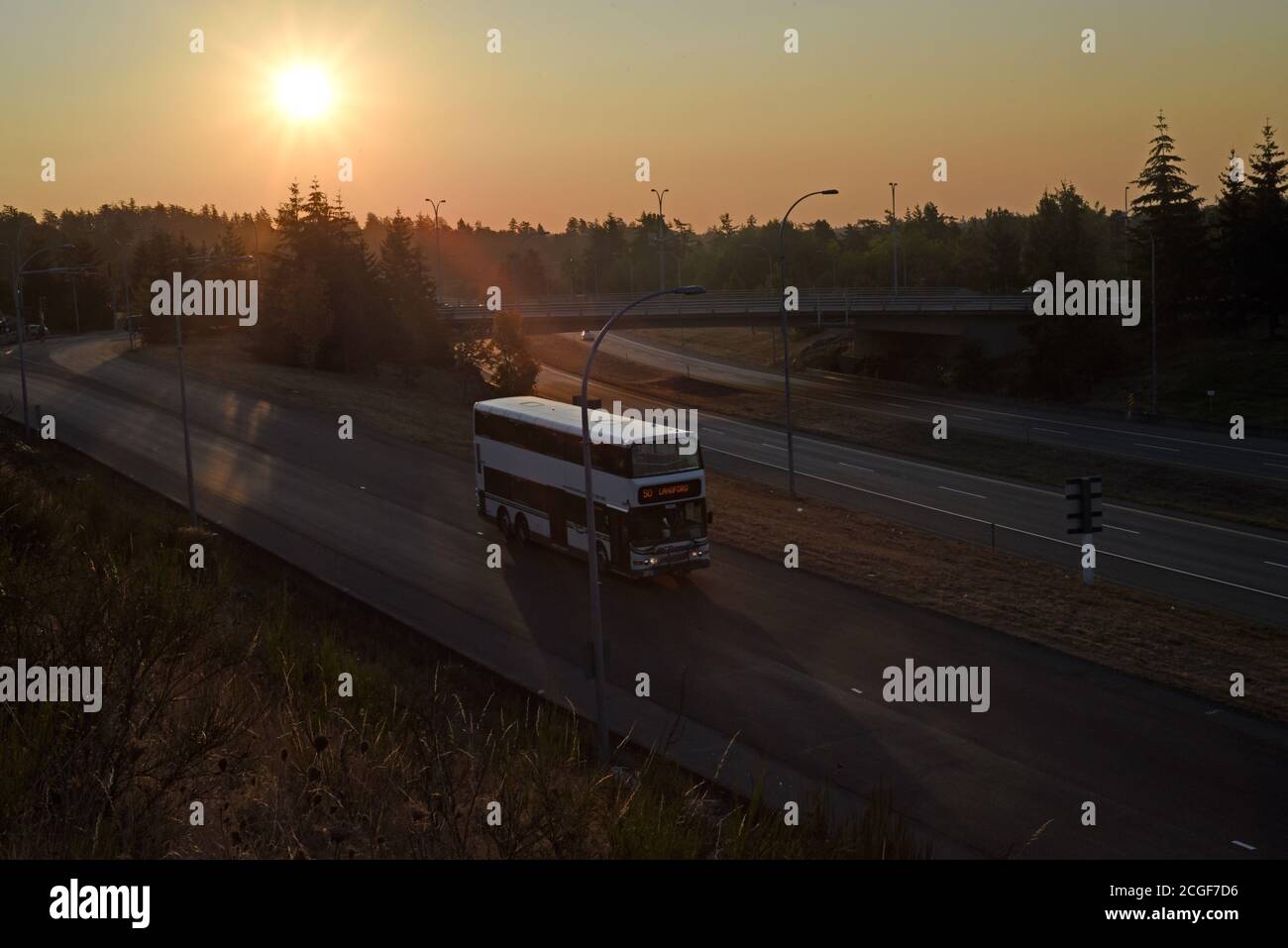 The rising morning sun is diffused by wildfire smoke as a double decker ...