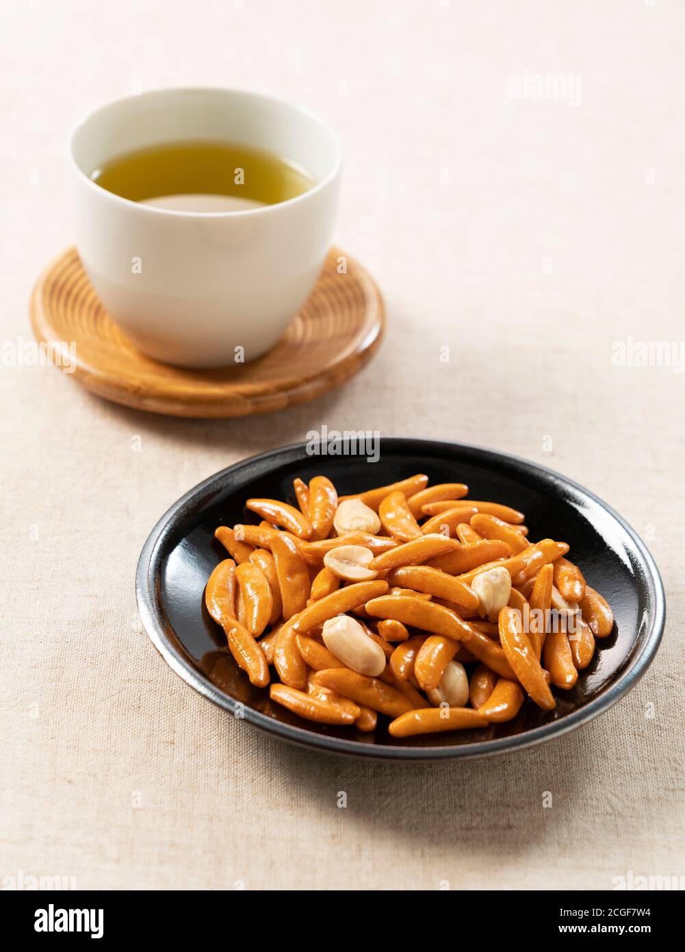 Green tea and crispy rice crackers with roasted peanuts placed on a ...