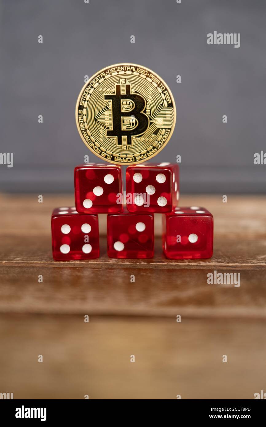 a golden Bitcoin coin stands on a stack of red dice Stock Photo - Alamy