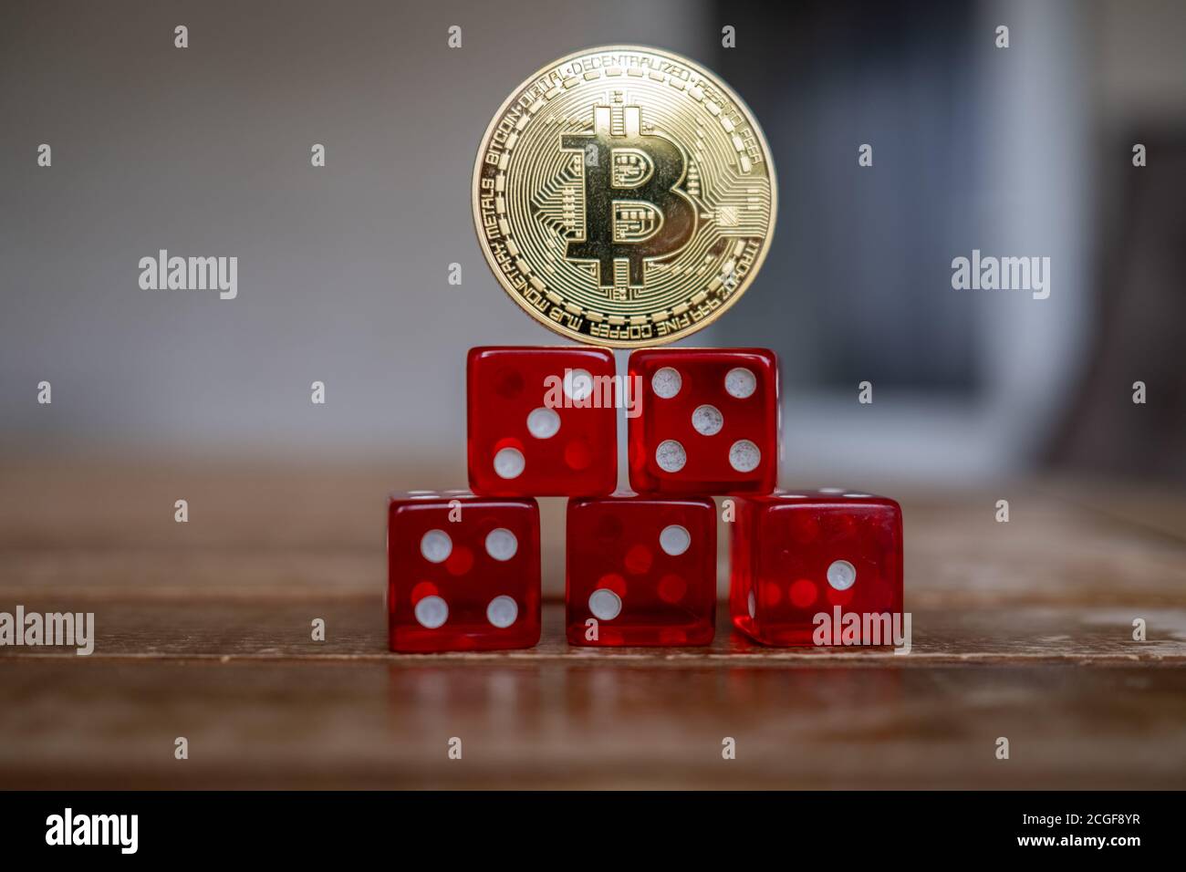 a golden Bitcoin coin stands on a stack of red dice Stock Photo - Alamy