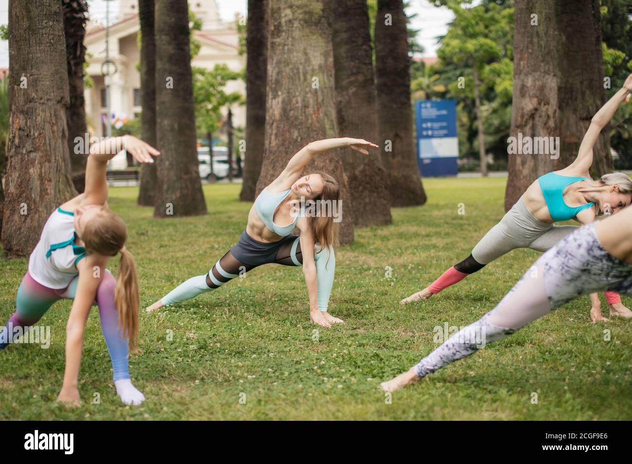 Fit young advanced yoga students doing extended triangle pose outdoors ...
