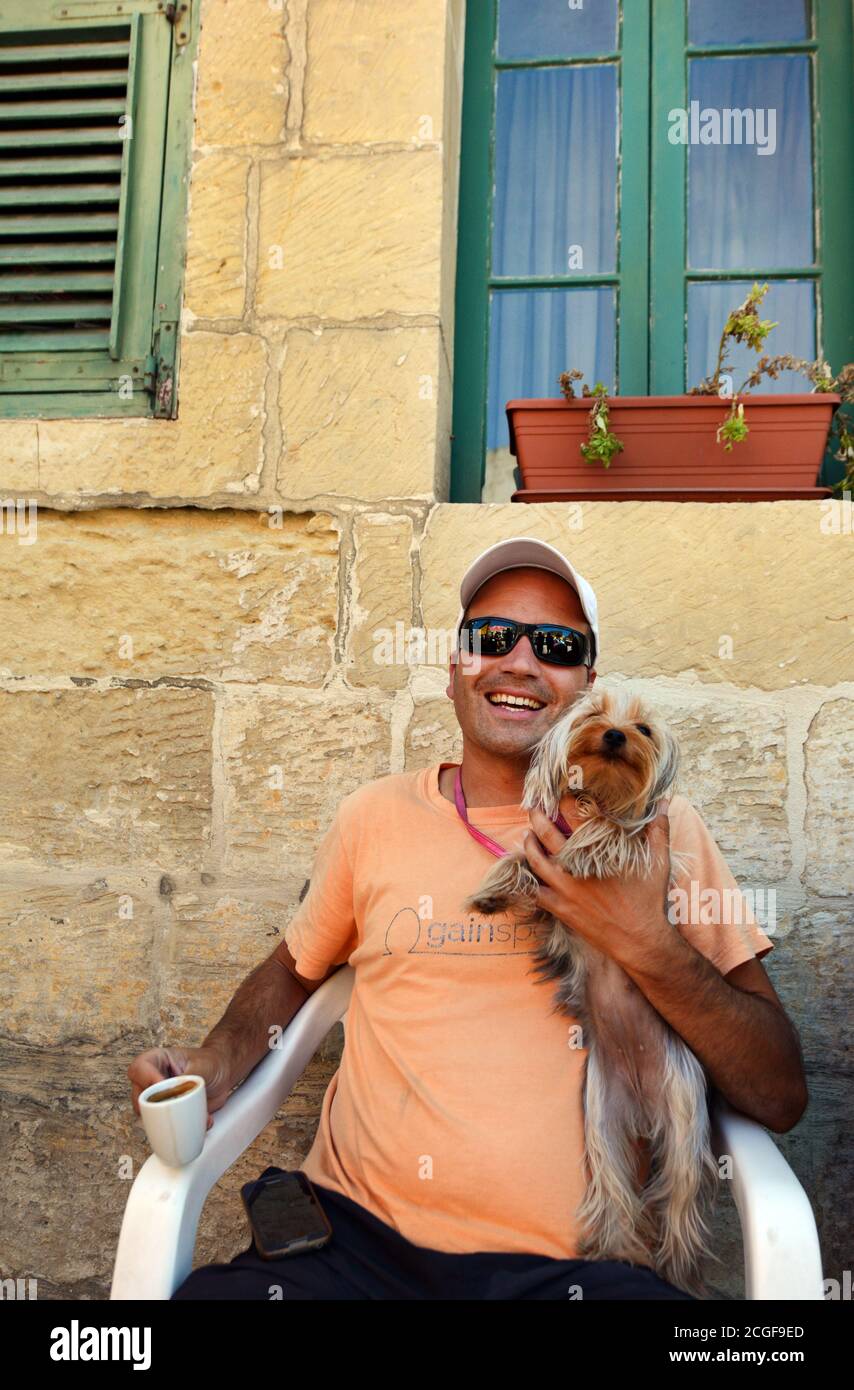 A Maltese man holding his pet dog Stock Photo - Alamy