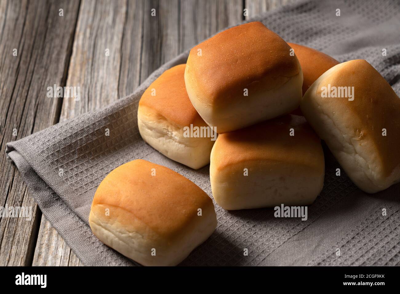 Close up of a dinner roll pan placed against an old wooden backdrop ...