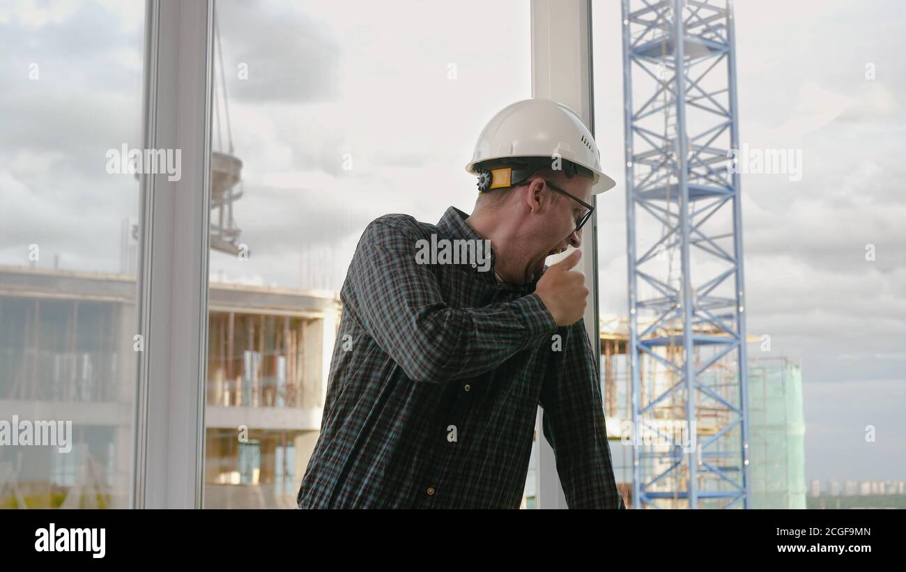 The worker in white hard hat was tired from work with contruction site ...