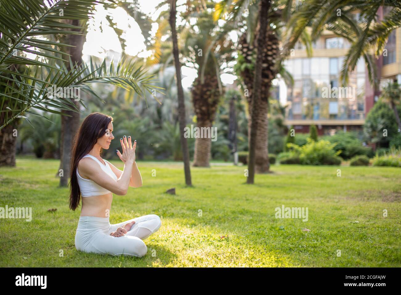Woman In the lotus posture over green grass, outdoor, side view Stock ...