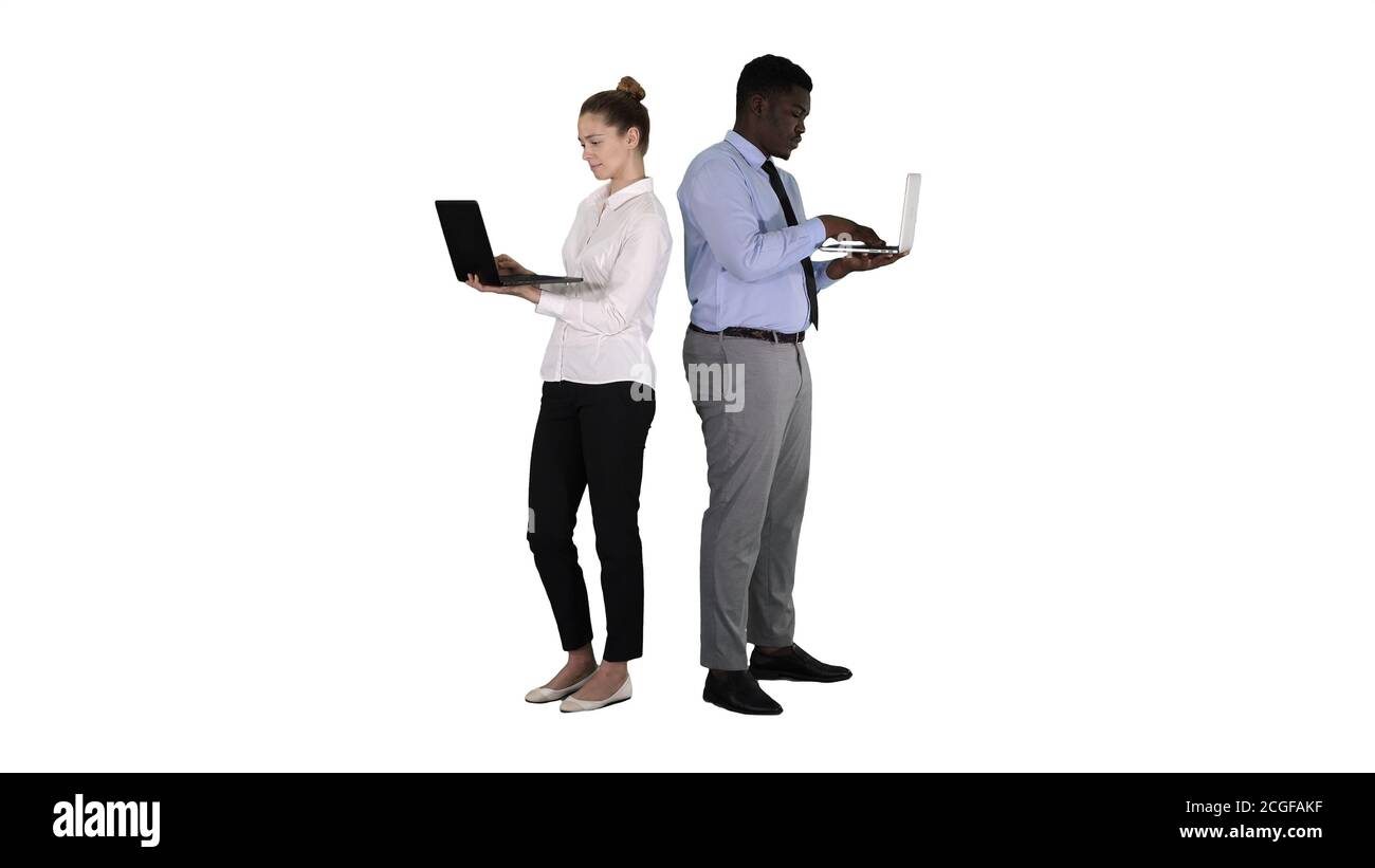 Couple back to back standing and working on laptops on white background ...