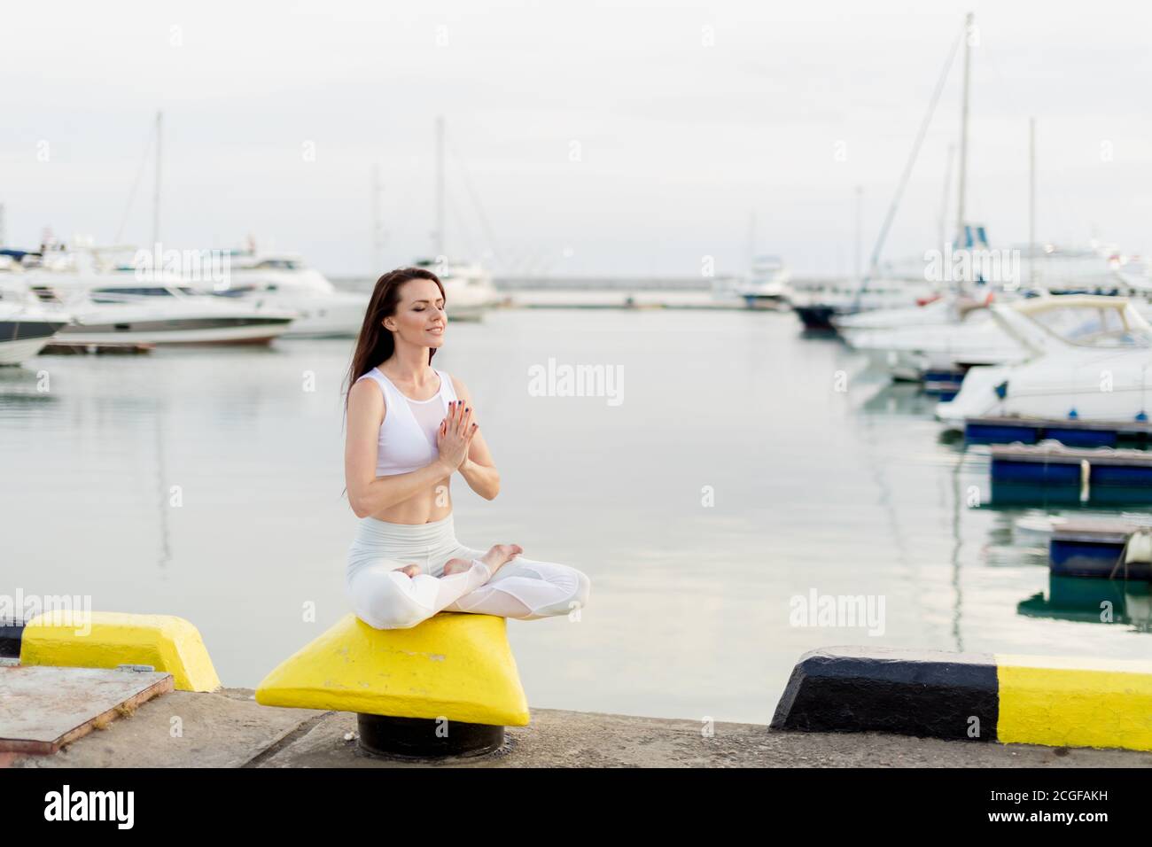 Young attractive woman practicing Lotus exercise over Sea water ...