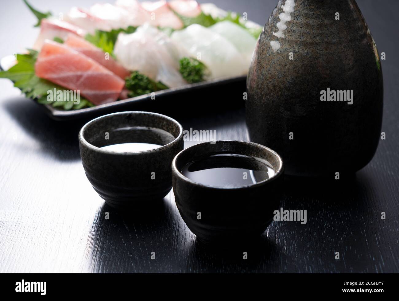 Sake and sashimi on a black background Stock Photo - Alamy