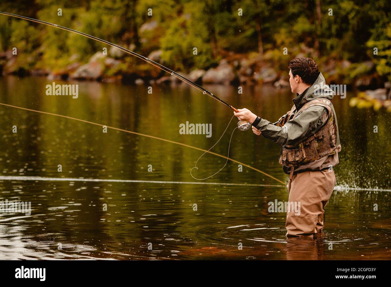 Fisherman using rod fly fishing in mountain river Stock Photo - Alamy