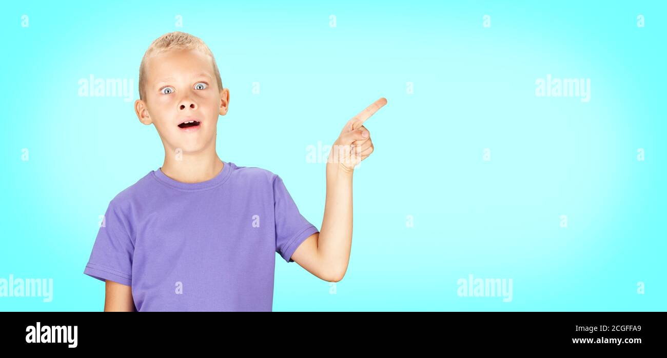 Funny surprised boy pointing with hand and finger. Over blue background ...