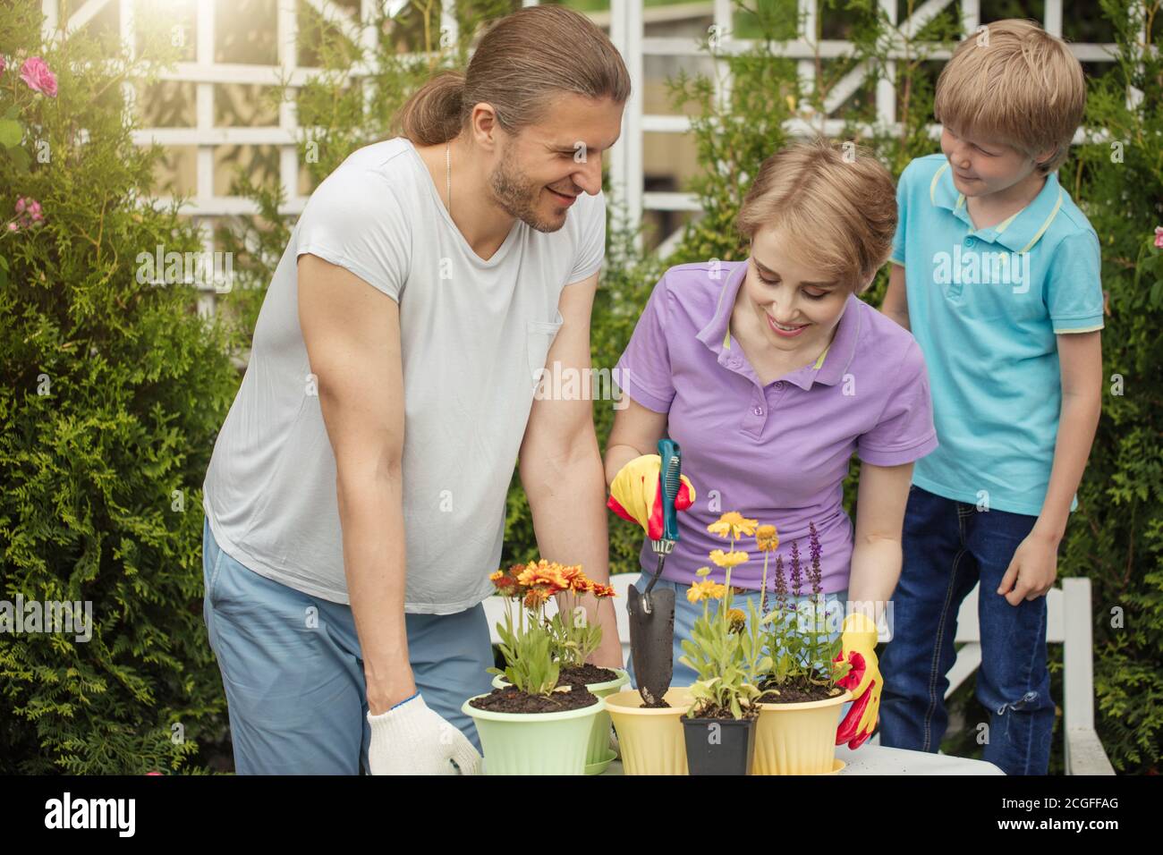 Happy family gardening together and taking care of flowers and plants ...