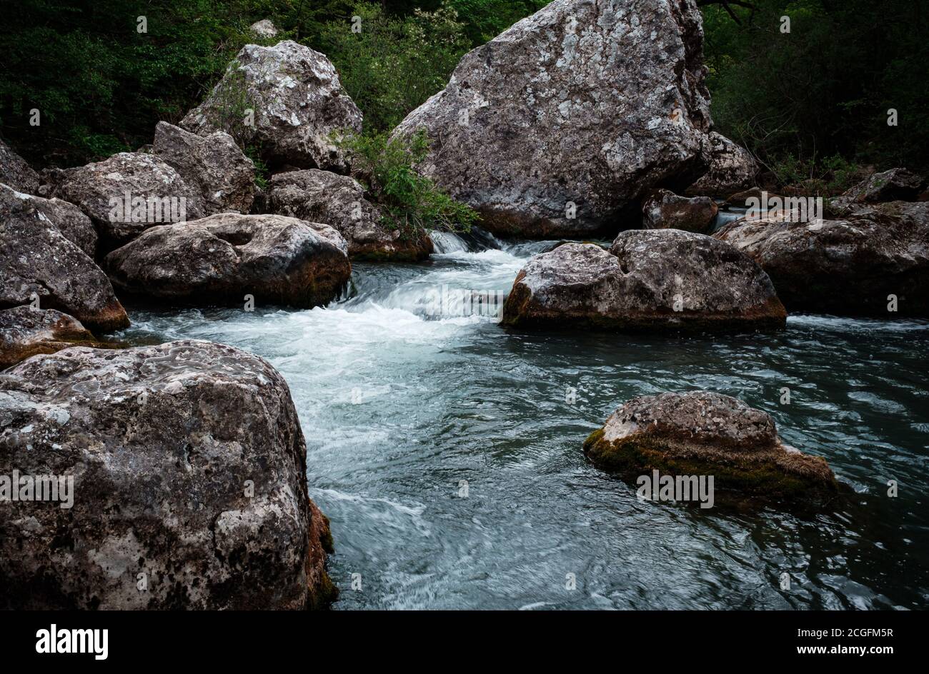 Full-flowing river in a sunny forest. Stream flowing over mossy rocks ...