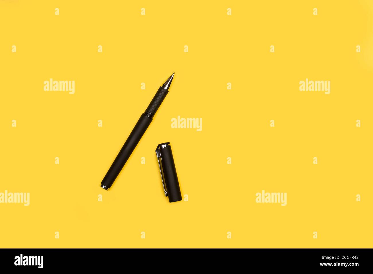 An open black ballpoint pen on a yellow background with copy space ...