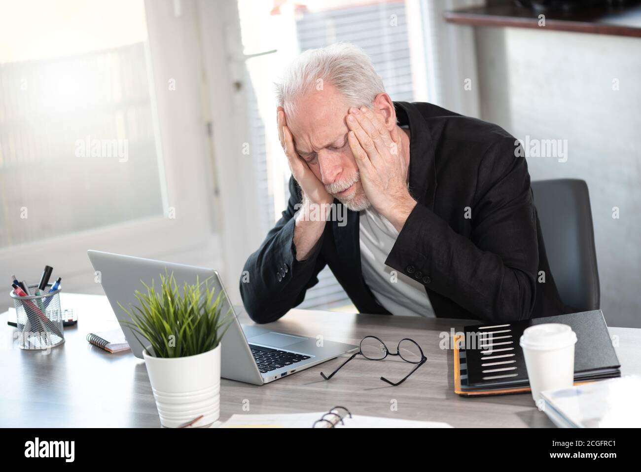 Overworked and exhausted senior businessman sitting at workplace Stock ...