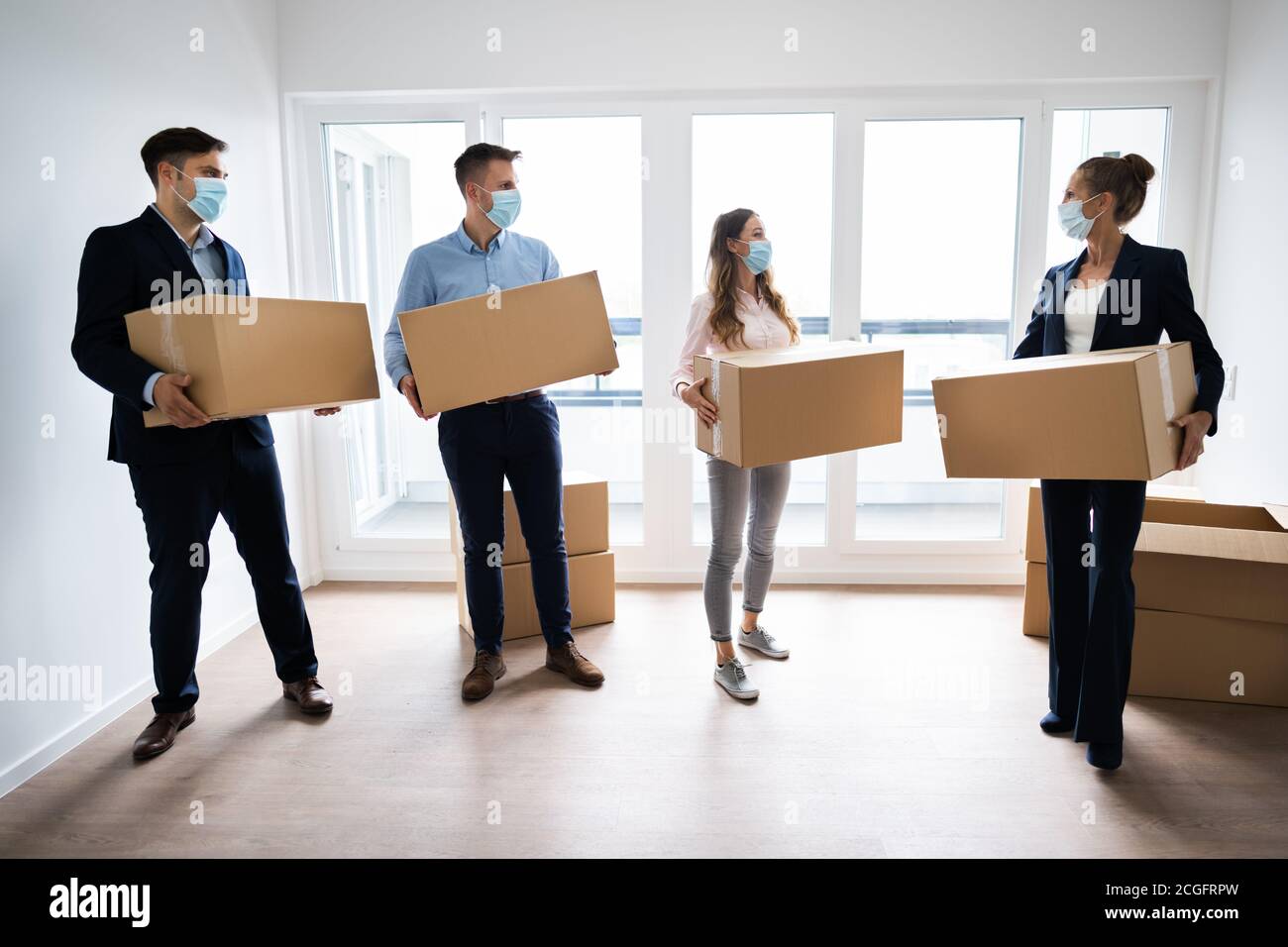 Office Relocation. Executives Moving Cardboard Boxes In Face Masks ...